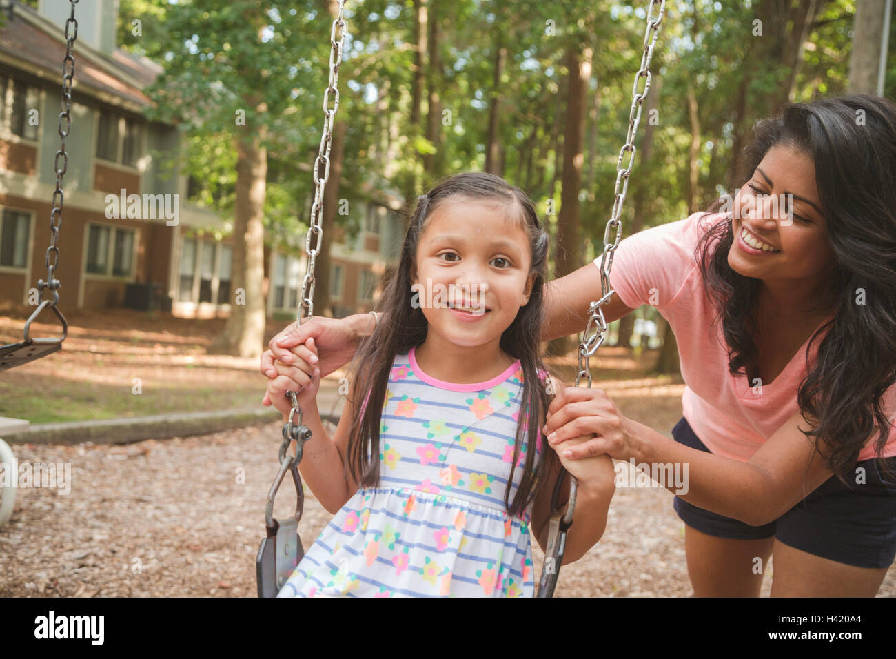 Hispanic mother pushing daughter in playground swing Stock Photo - Alamy