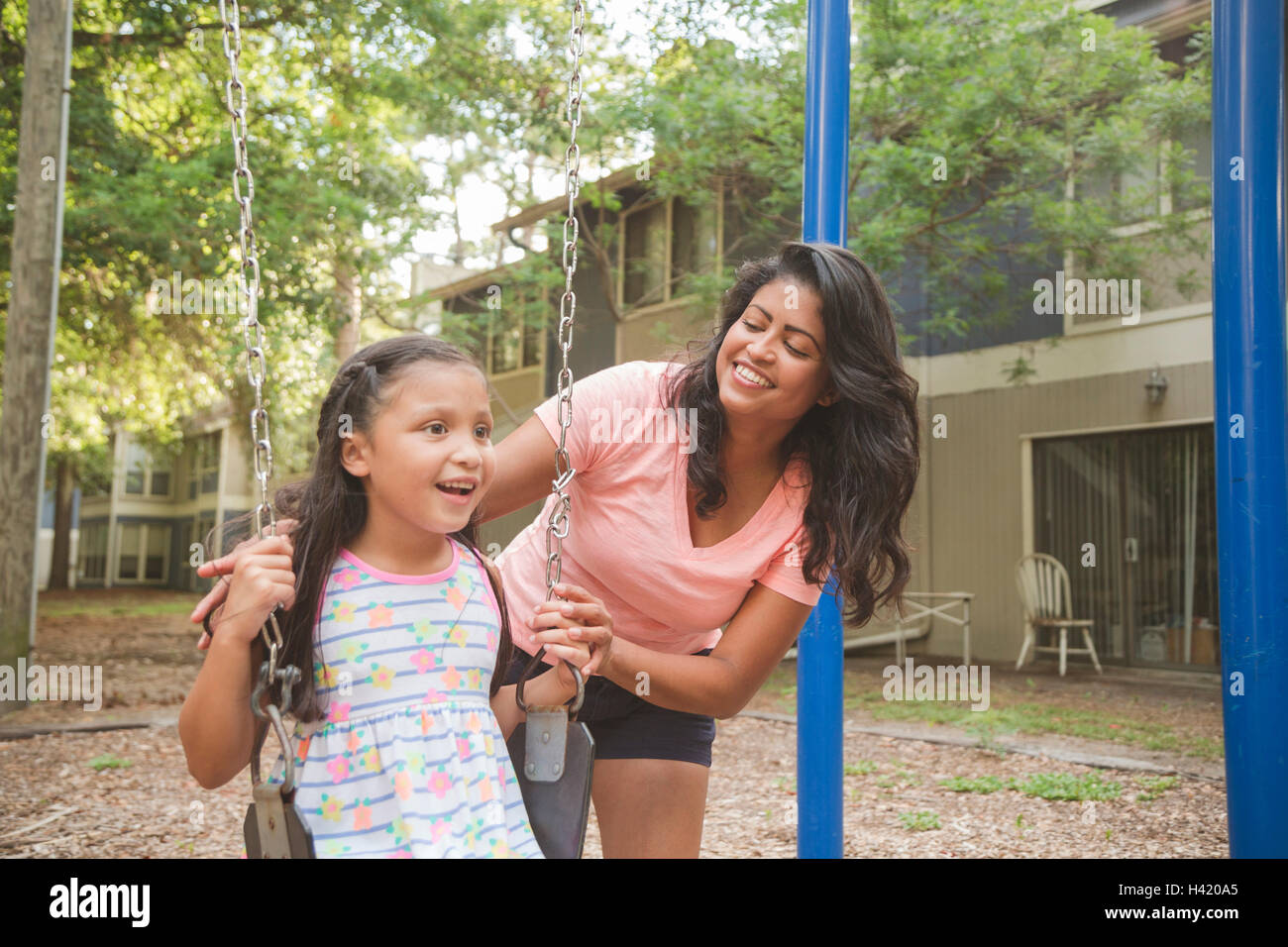 Hispanic mother pushing daughter in playground swing Stock Photo - Alamy