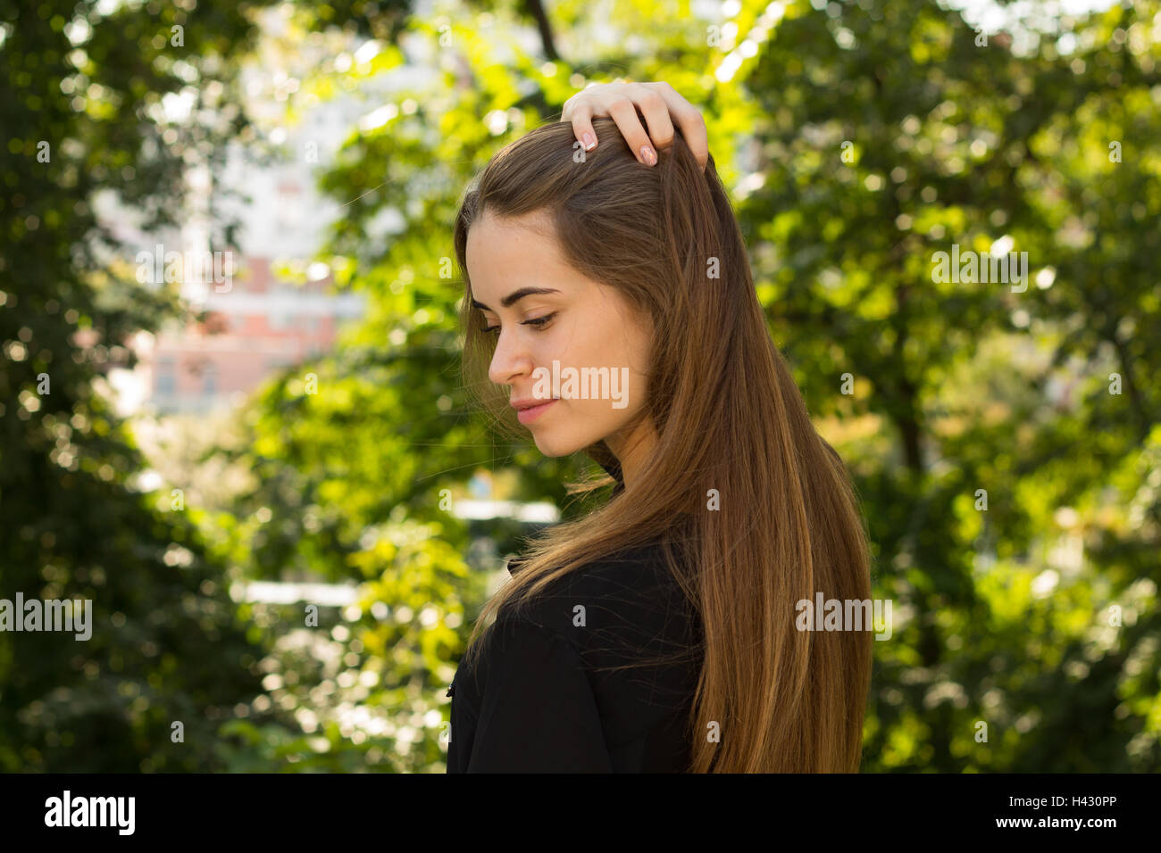 Young woman standing back on the background of trees Stock Photo - Alamy