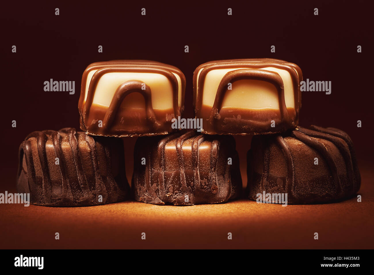 Closeup macro view of five chocolate candies, on brown background Stock ...