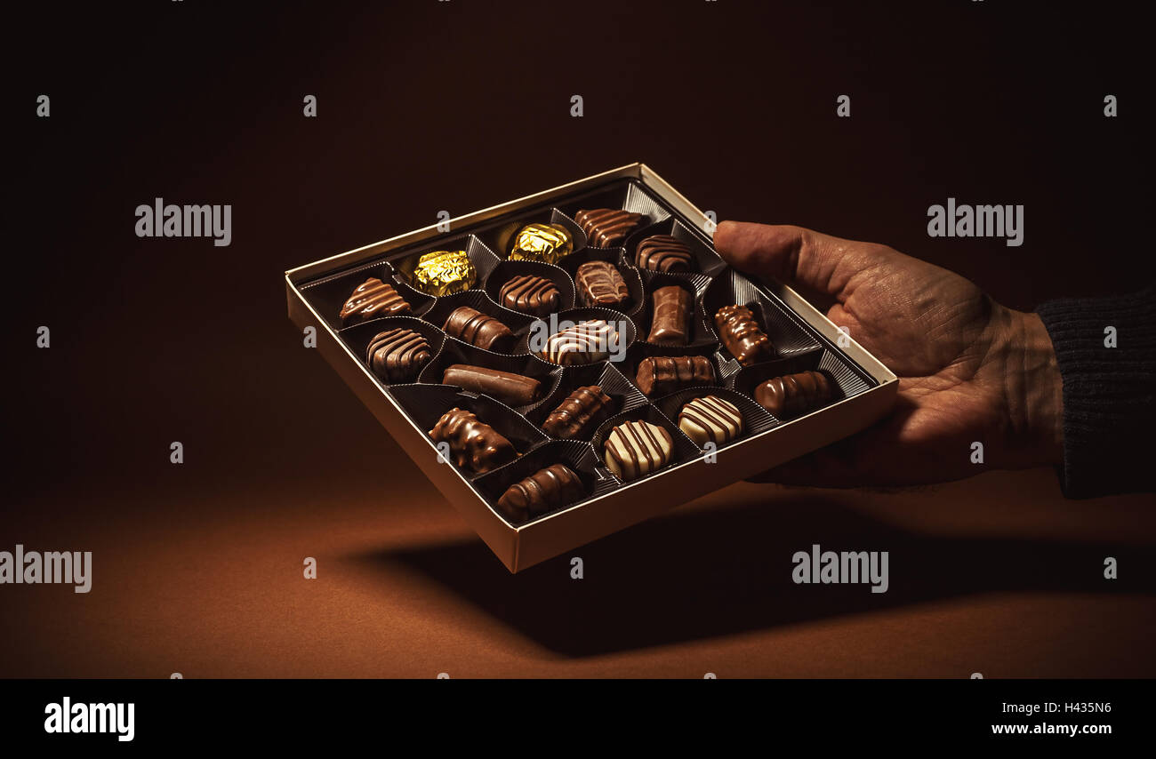 Male hand is holding an open box of chocolates Stock Photo - Alamy