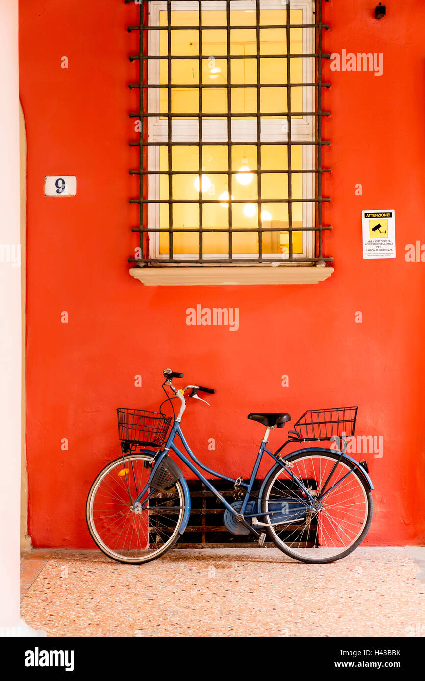 Blue bicycle leaning on orange wall under window Stock Photo - Alamy