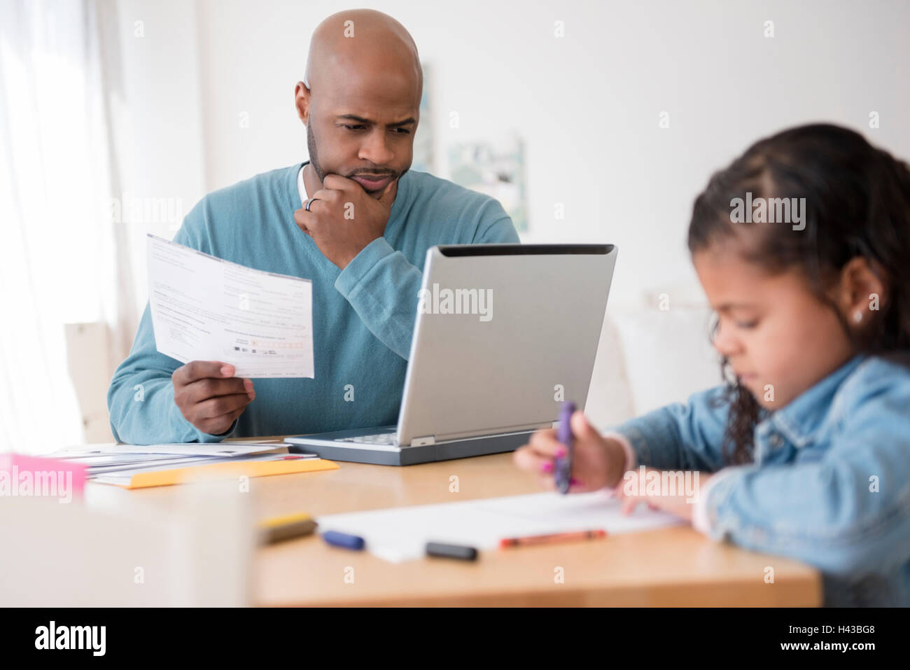 Daughter coloring with crayons while father uses laptop Stock Photo - Alamy