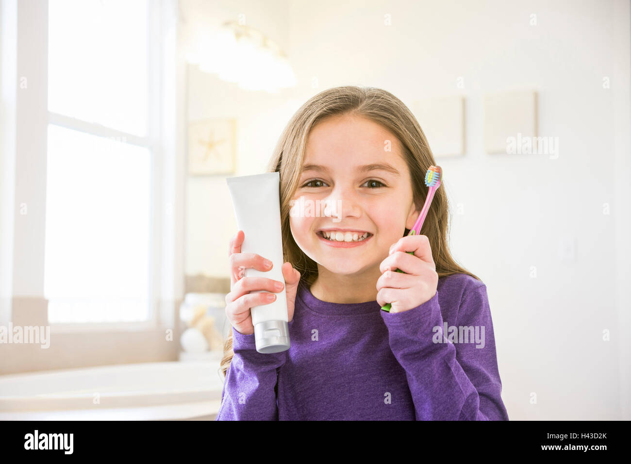 Smiling Caucasian girl holding toothbrush and toothpaste tube in ...