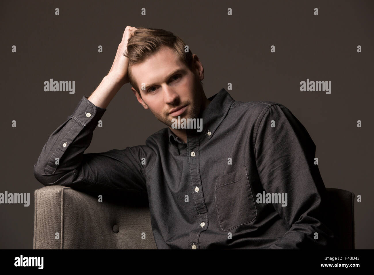 Serious Caucasian man with hand in hair Stock Photo - Alamy