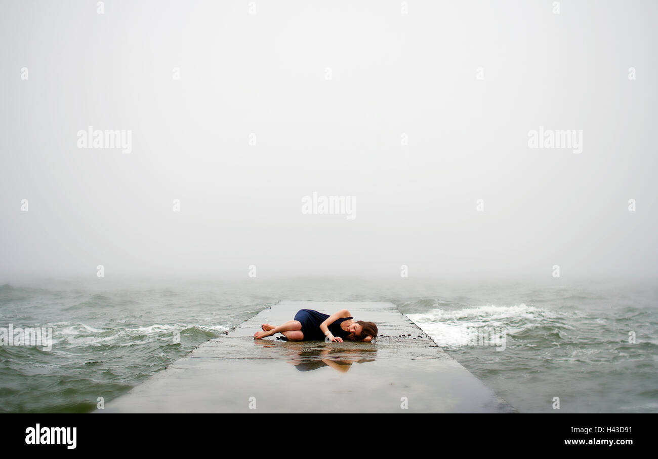 Caucasian woman laying on dock in ocean waves Stock Photo - Alamy