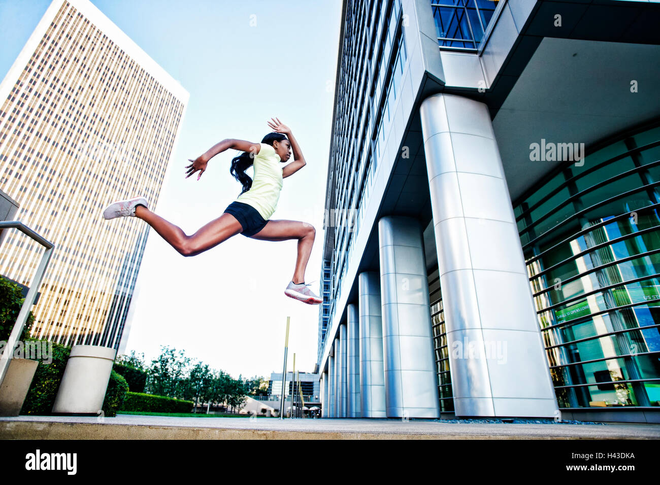 Black woman running and jumping on city sidewalk Stock Photo - Alamy