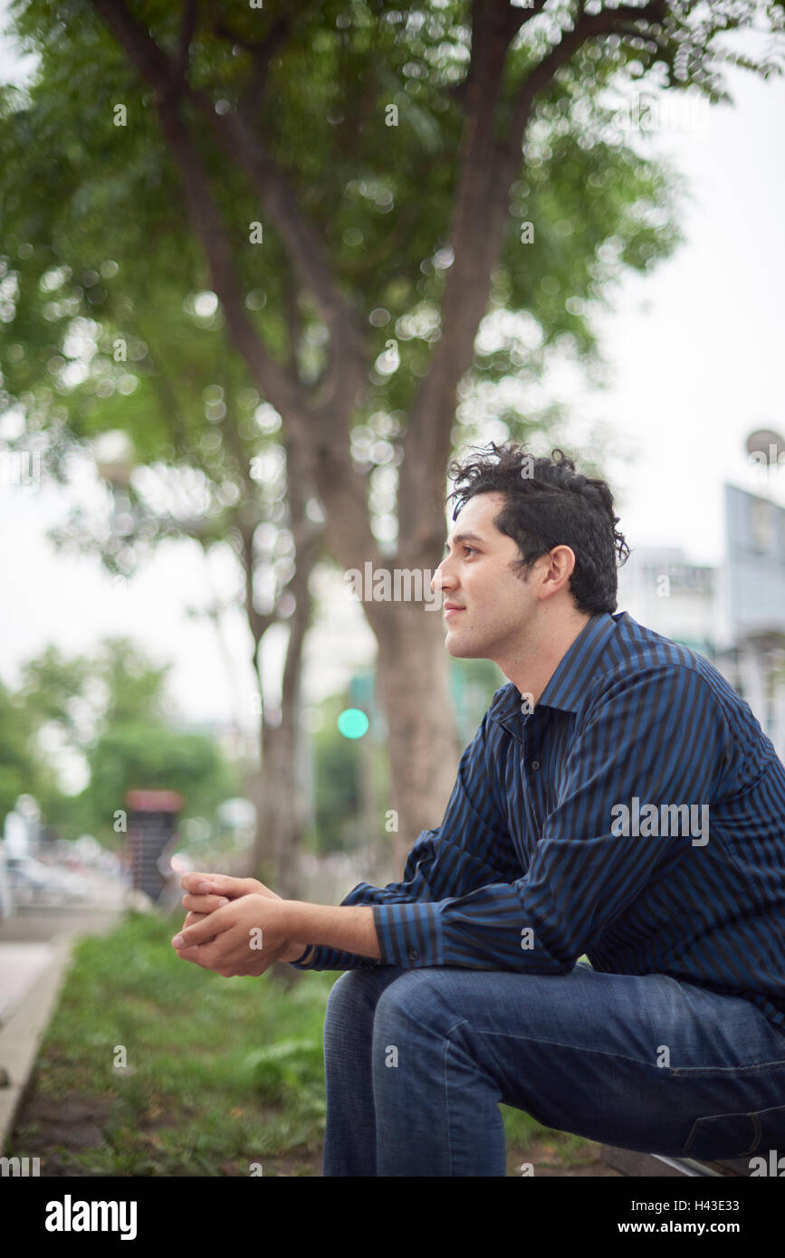 Smiling Hispanic man sitting on bench Stock Photo - Alamy