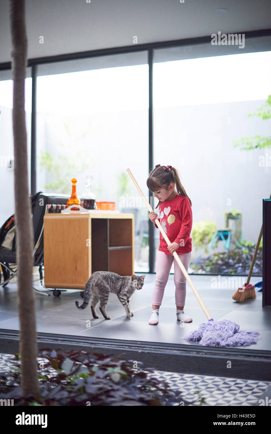 Hispanic girl watching cat and mopping floor Stock Photo - Alamy