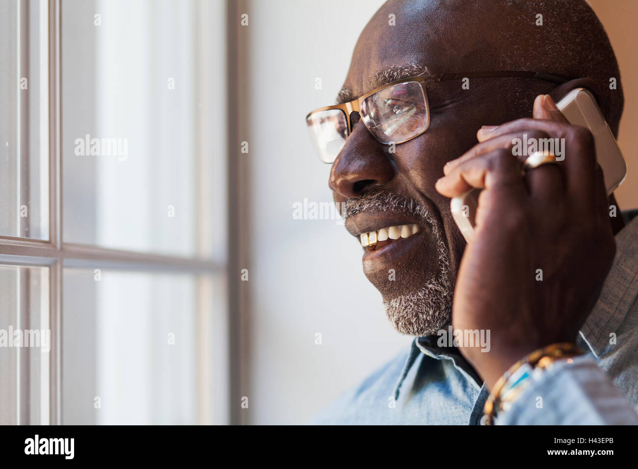 Man talking on cell phone near window Stock Photo - Alamy