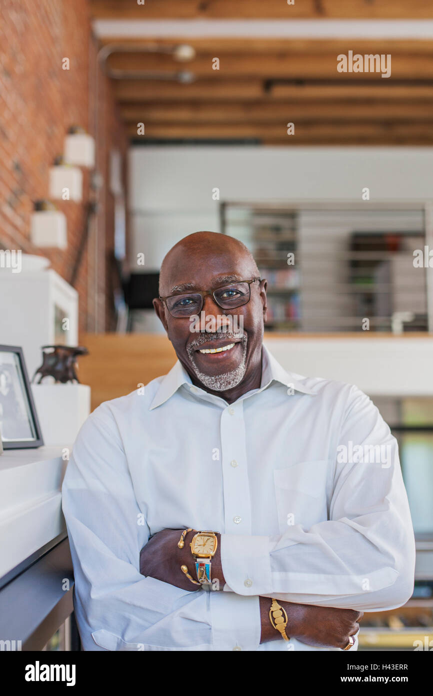 Smiling man with arms crossed leaning on mantle Stock Photo - Alamy