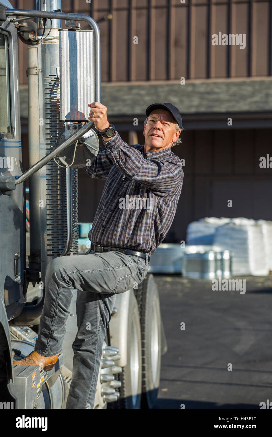 Caucasian man climbing into semi-truck Stock Photo - Alamy