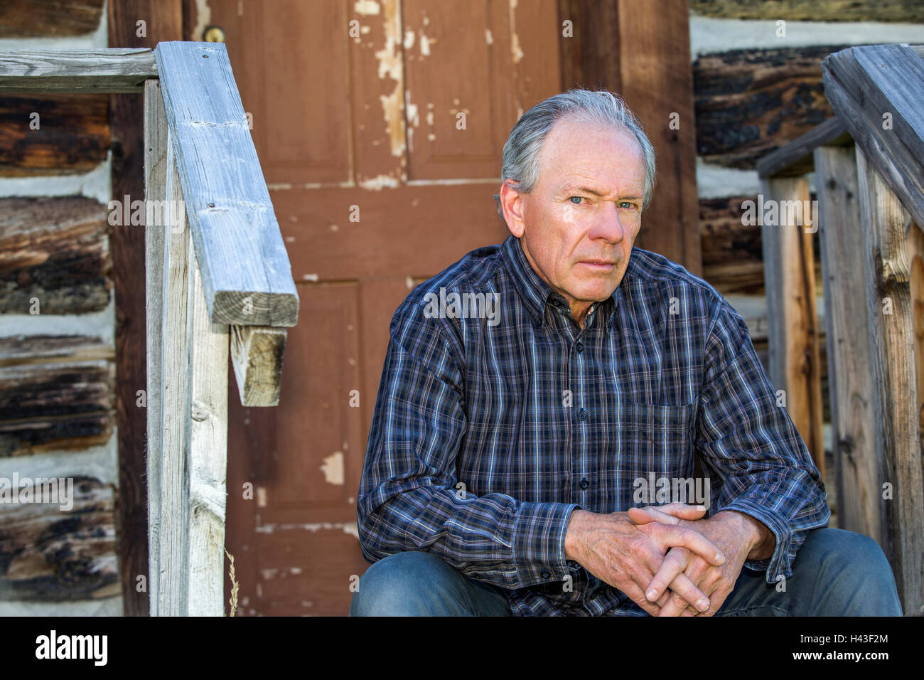 Serious Caucasian man sitting on wooden front stoop Stock Photo - Alamy