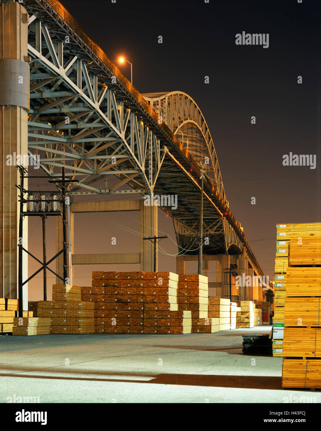 Piles of lumber under bridge at night Stock Photo - Alamy