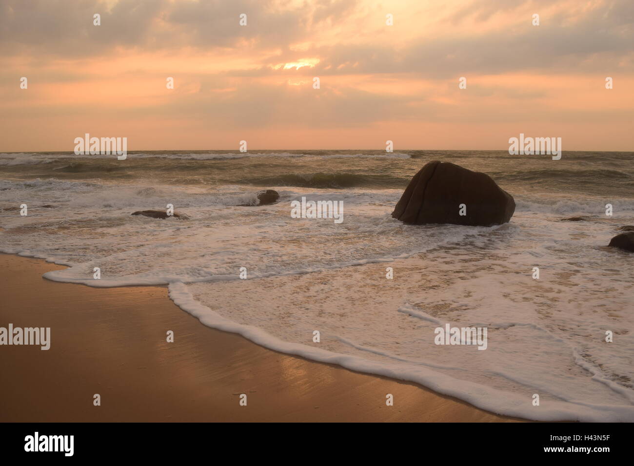 tropical beach in sunset with wave and rock Stock Photo - Alamy