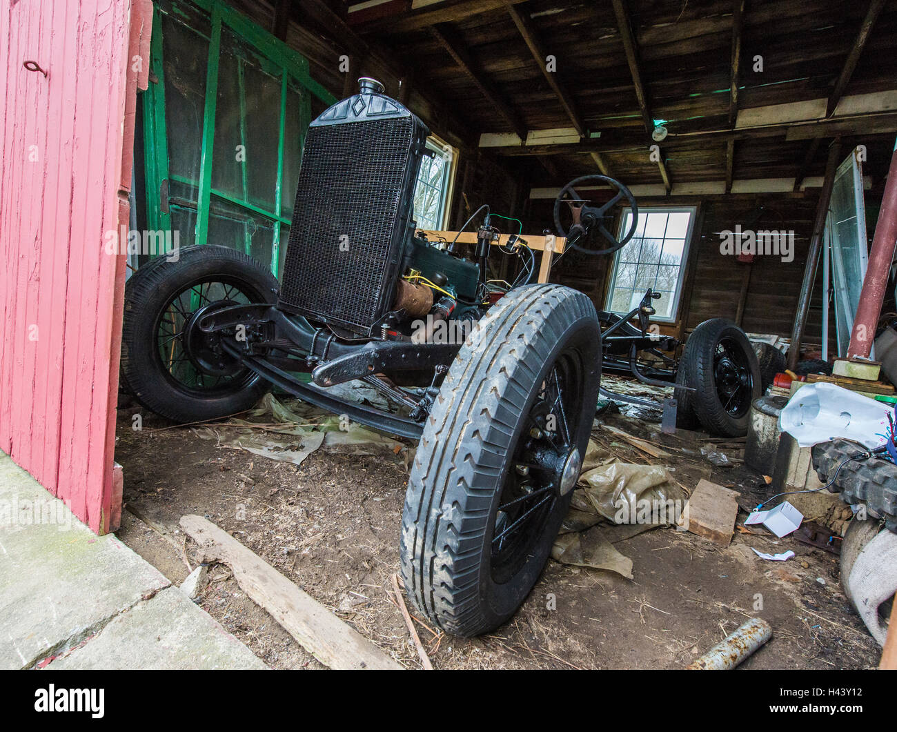 A frame and engine of a Model A Ford sits in a barn awaiting ...