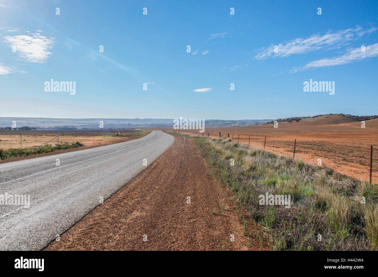 Wide open landscape with roadway in diminishing perspective and red ...