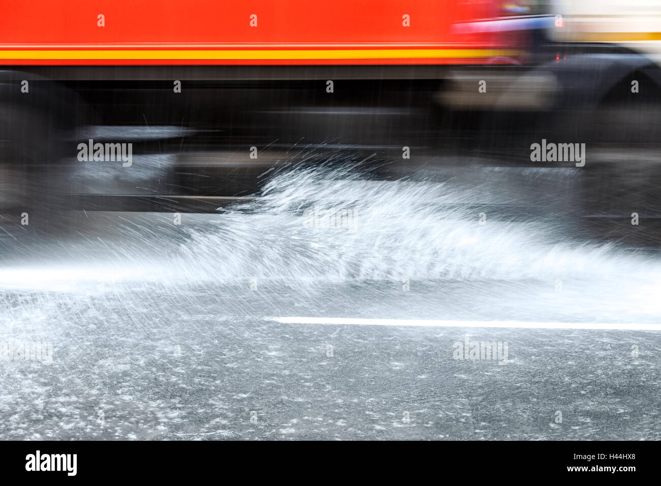 car driving on flooded city road and splashing rain water. abstract ...