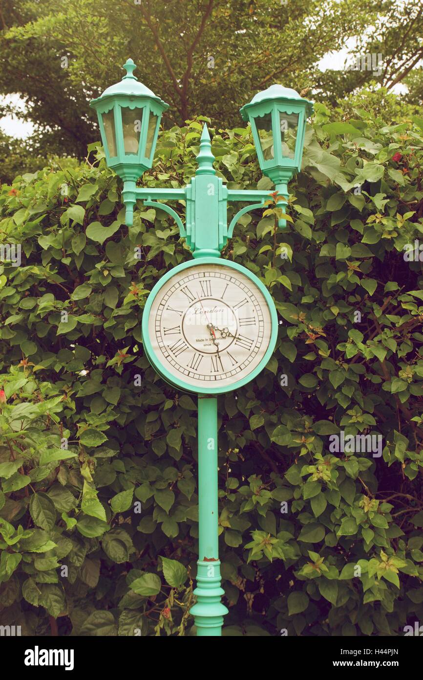 Turquoise vintage metal park clock on green tree leaf background Stock ...