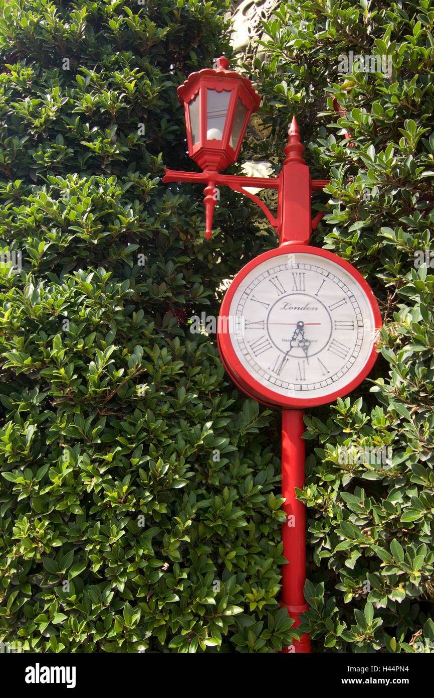 Red vintage metal park clock on green tree leaf background Stock Photo ...