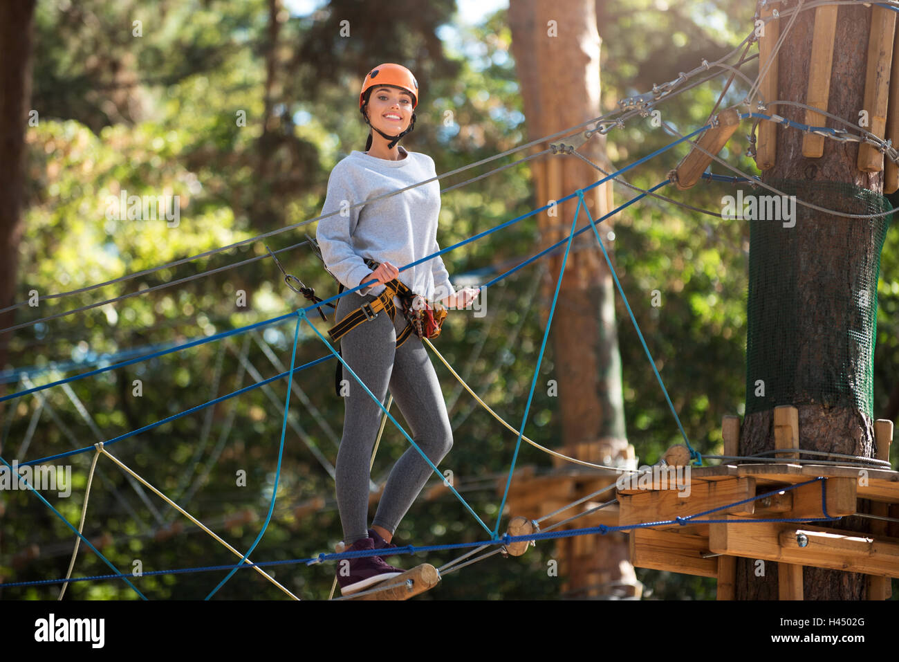 Positive charming woman standing on the rope ladder Stock Photo - Alamy