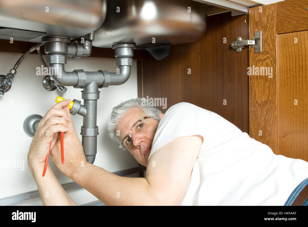 plumber at work in a kitchen fixing a sink Stock Photo - Alamy
