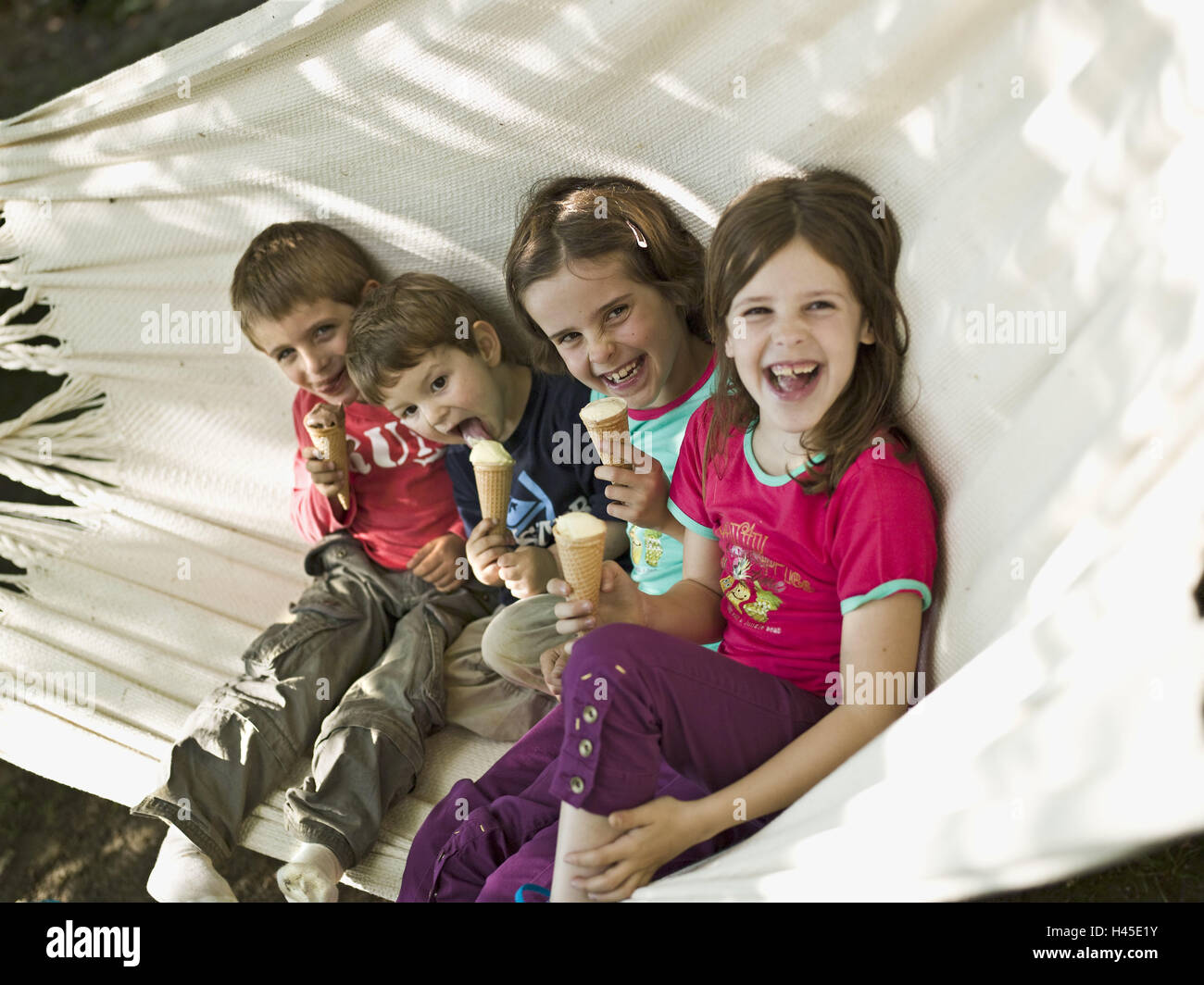 Childre in hammock, eating ice cream, side view Stock Photo - Alamy