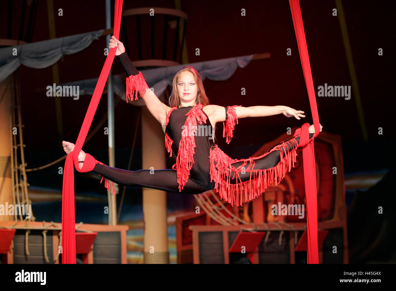 A girl performs aerial silk, an acrobatic display hanging from a fabric ...