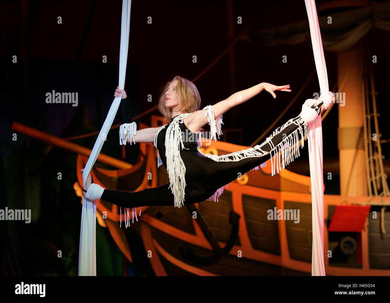 A girl performs aerial silk, an acrobatic display hanging from a fabric ...