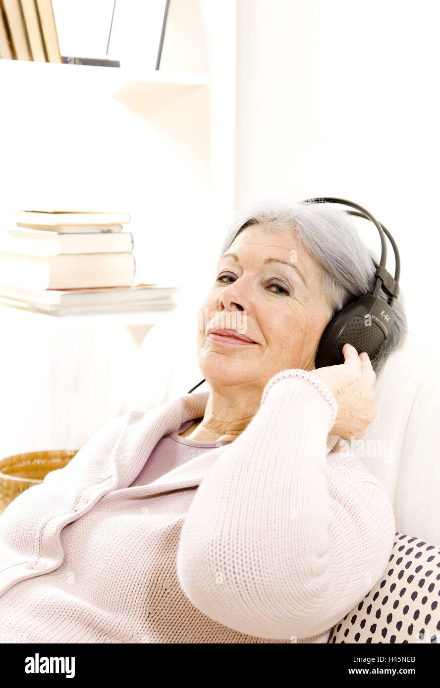Senior woman, armchair, sitting, hearing music, headphones, music ...