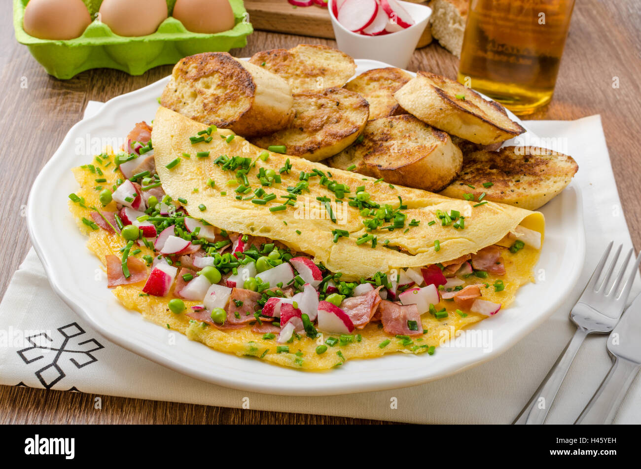 Omelette with spring vegetables and bacon, fresh peas and radish ...