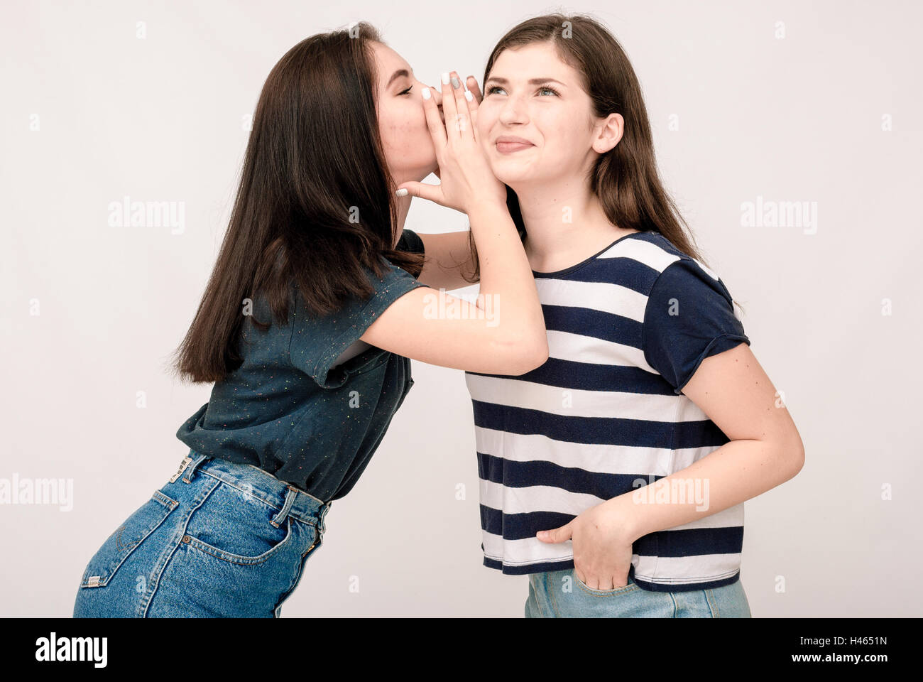 Portrait of a two girls gossip on gray background Stock Photo - Alamy