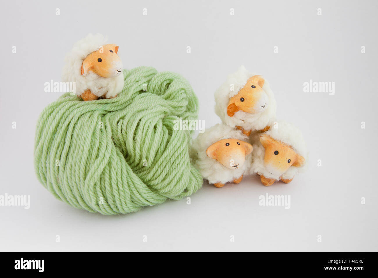 Cute sheep playing together with a ball of green wool Stock Photo - Alamy