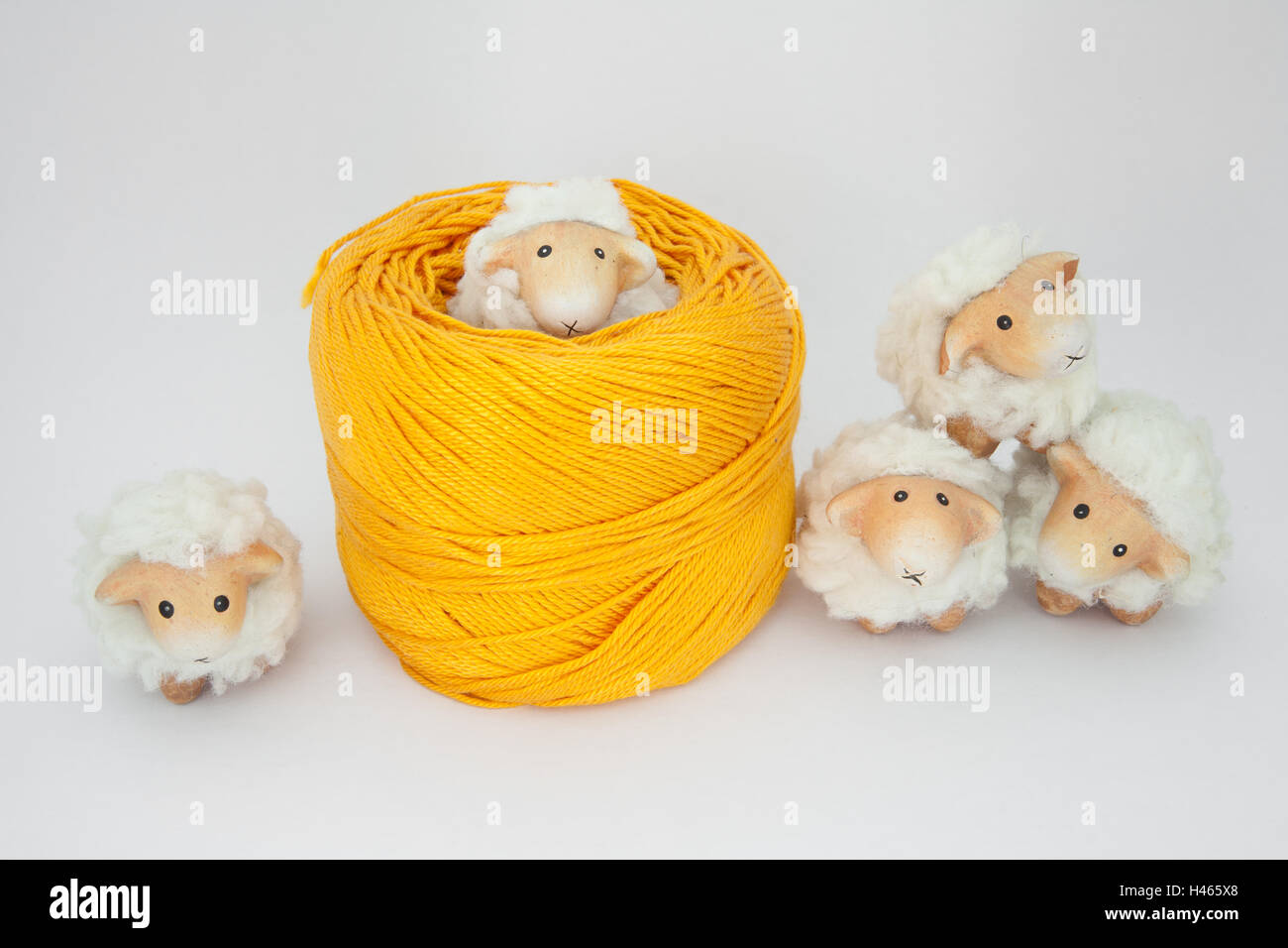 Cute sheep playing together with a ball of yellow wool Stock Photo - Alamy