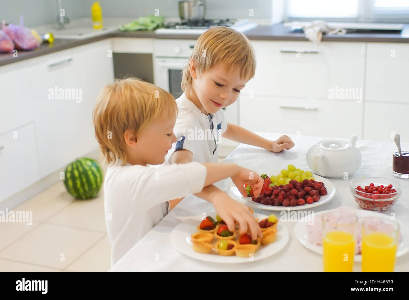 Two boys preparing breakfast in white kitchen Stock Photo - Alamy
