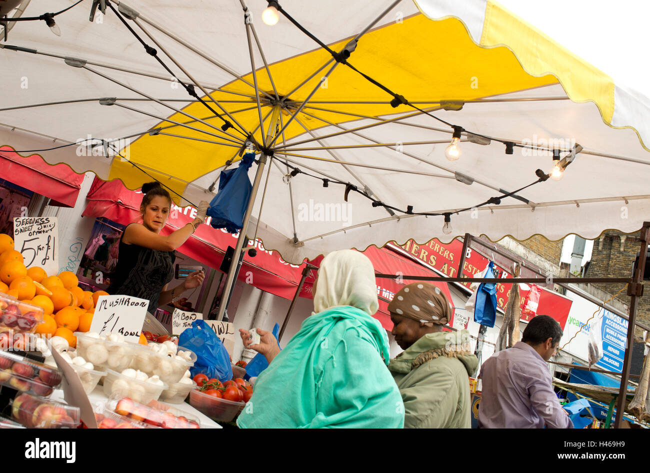 Hackney. Ridley Road market. Two women wearing head scarves shop at a ...