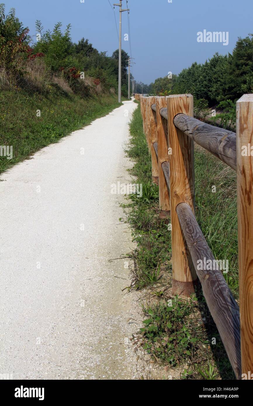 Dirt road for bike, in the summer. With parapet side built of wood ...
