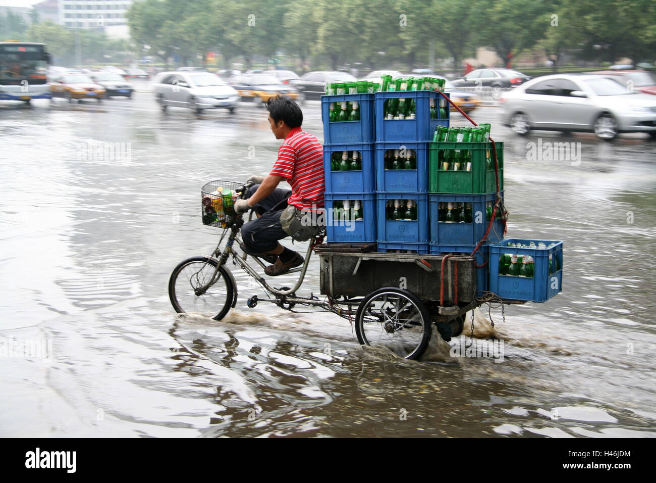 China, Peking, street scene, cyclist riding with heavy load through ...
