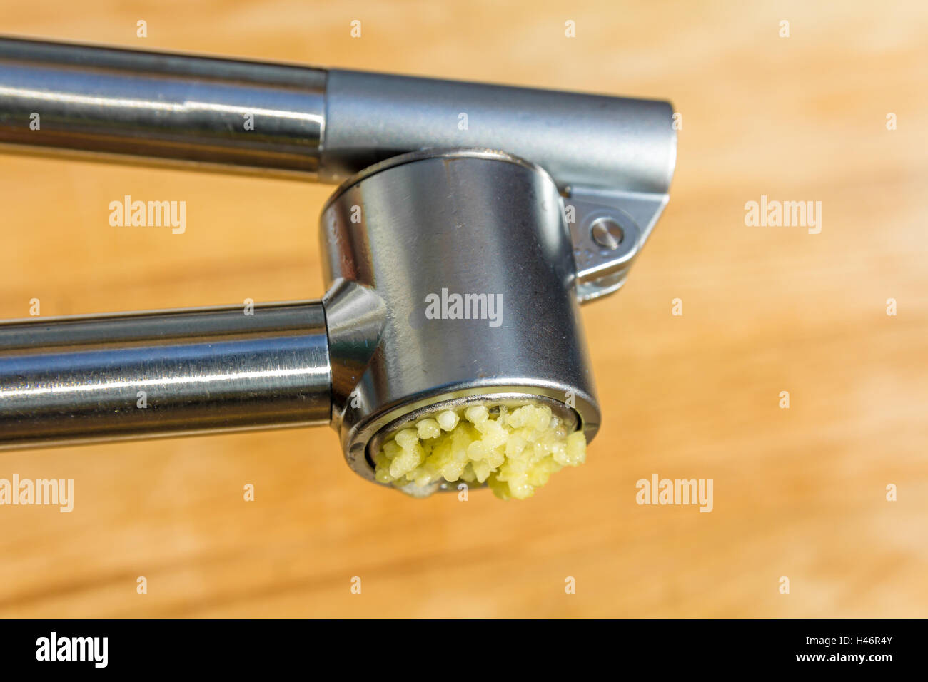 clove of garlic being crushed in garlic pres Stock Photo - Alamy