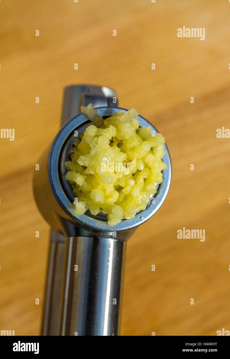 clove of garlic being crushed in garlic pres Stock Photo - Alamy
