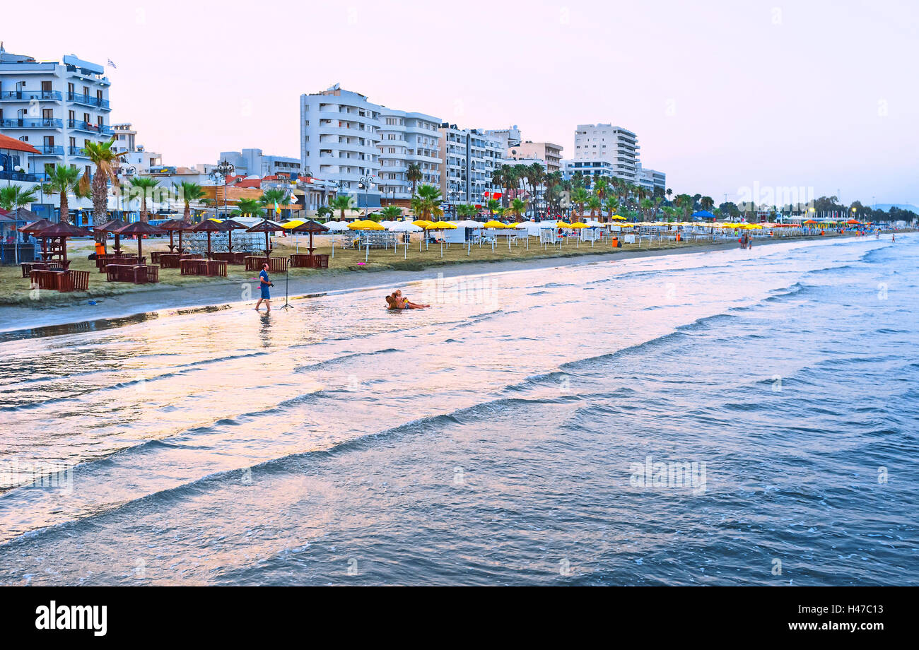 The evening beach with the numerous hotels and cafes on the background ...