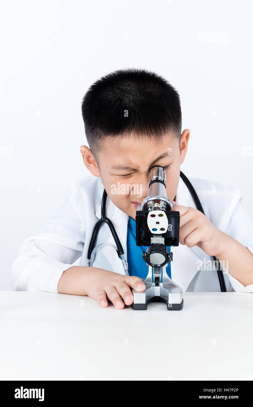 Asian Chinese boy working with microscope in isolated plain white ...