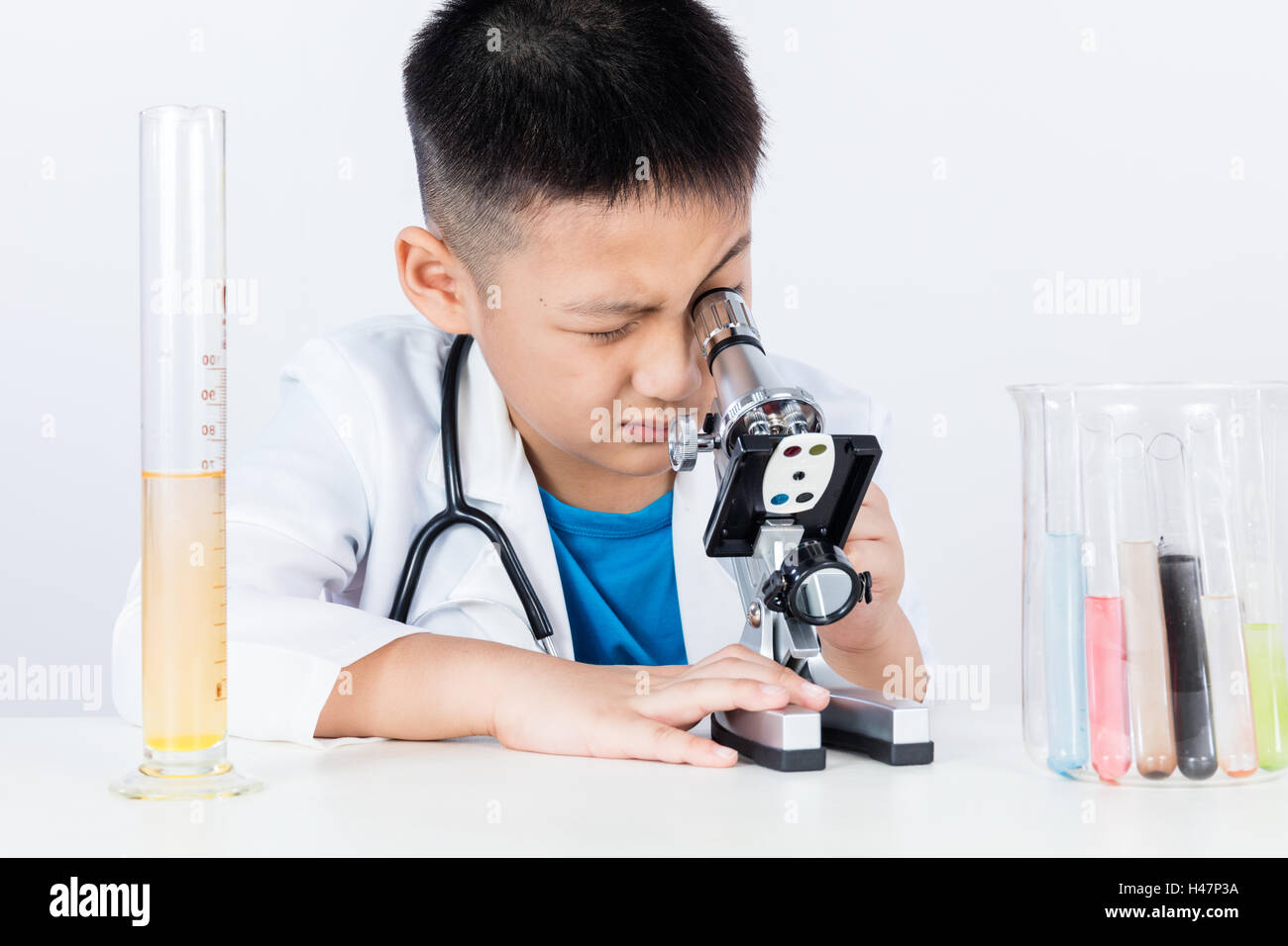 Asian Chinese boy working with microscope in isolated plain white ...