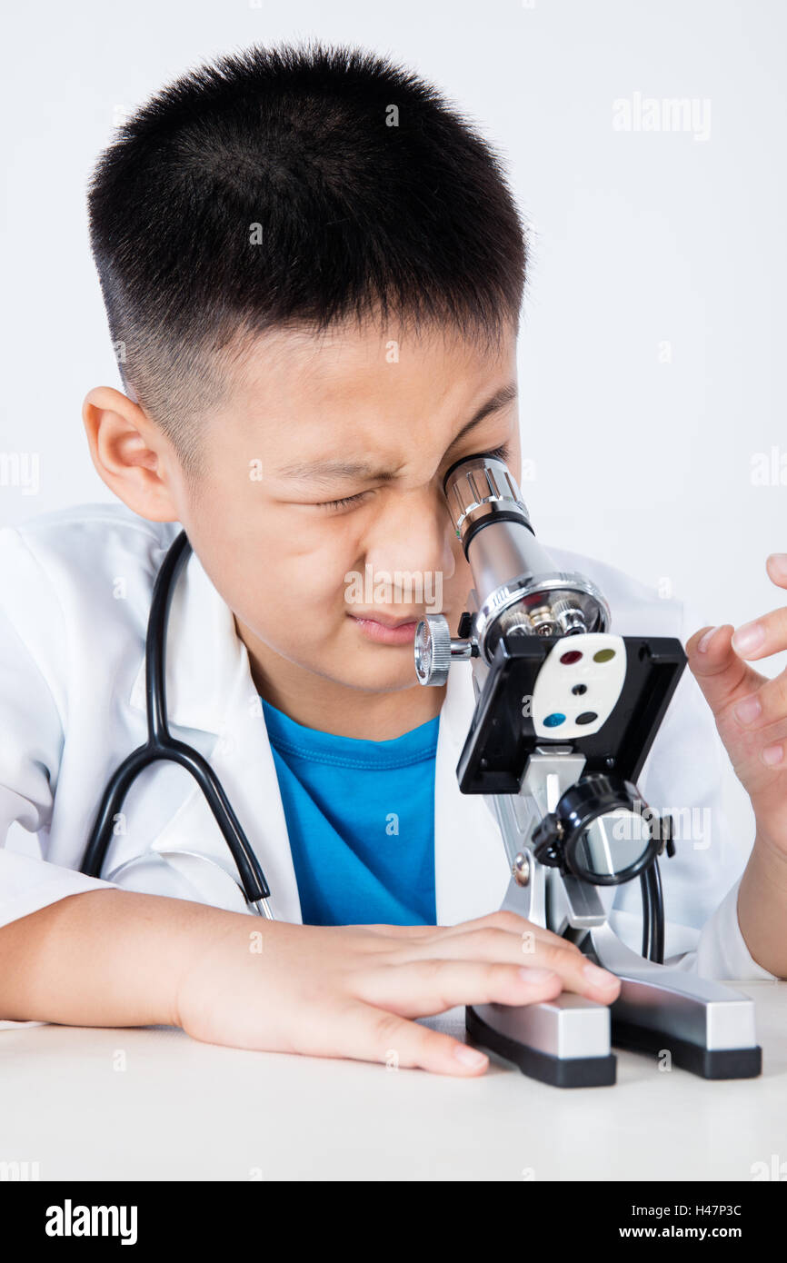 Asian Chinese boy working with microscope in isolated plain white ...