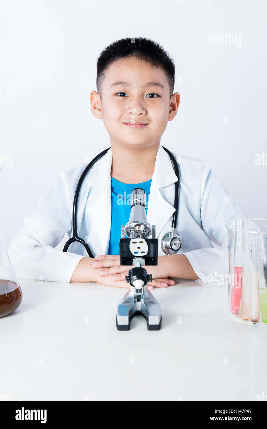 Asian Chinese boy working with microscope in isolated plain white ...