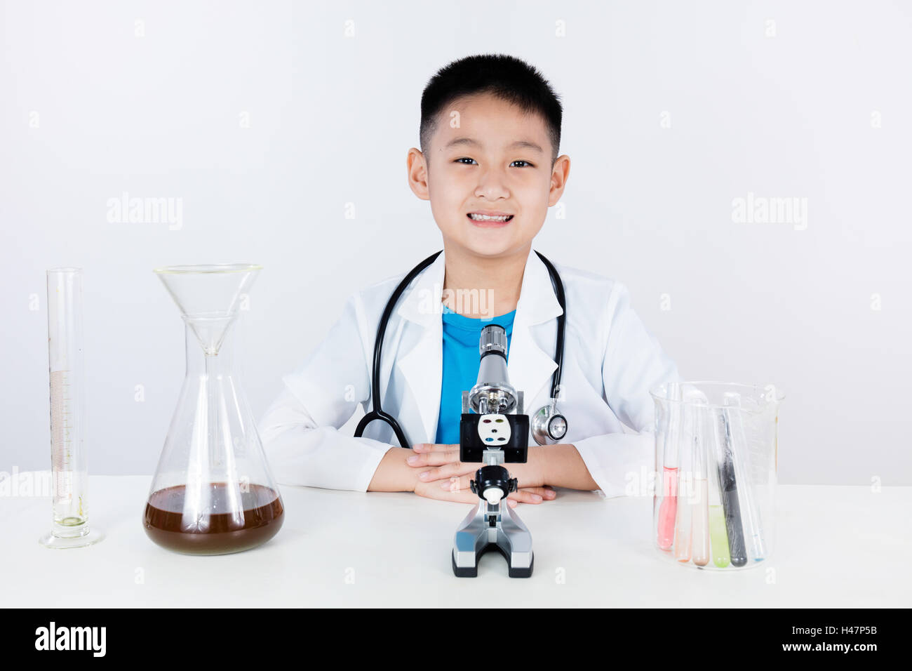 Asian Chinese boy working with microscope in isolated plain white ...