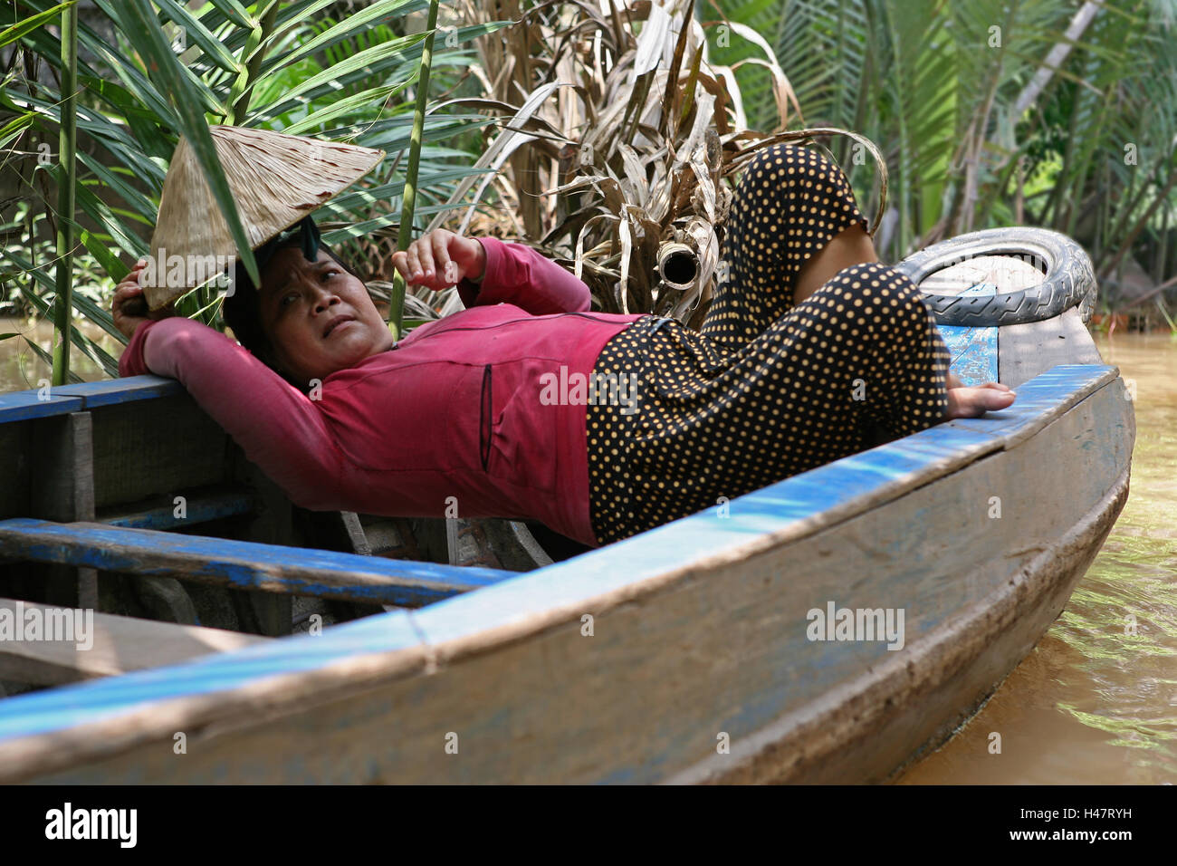 Woman relaxes in her canoe, backwater canal in the Mekong Delta, Tan An ...