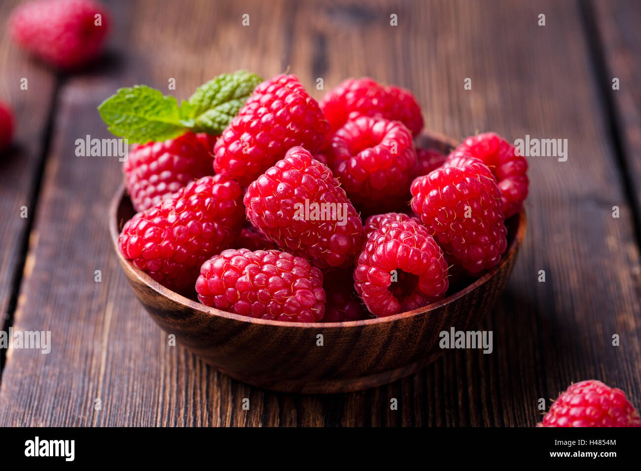Ripe sweet raspberries in bowl on wooden table Stock Photo - Alamy