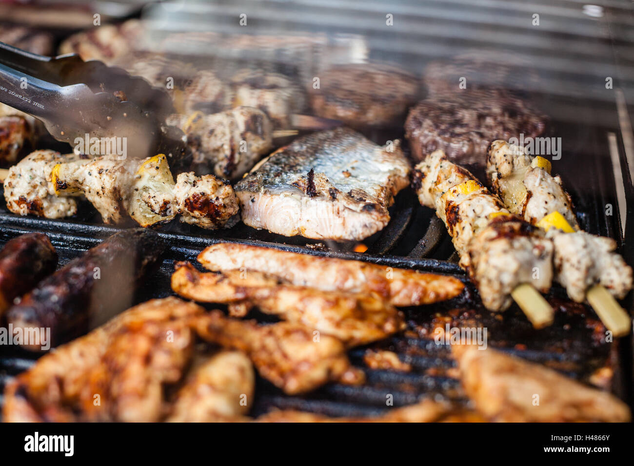 Various meats and fish grilling on a gas barbeque in the back garden ...