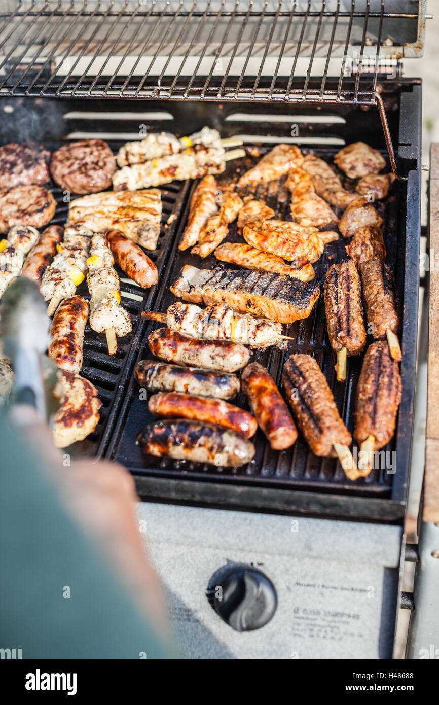 Various meats and fish grilling on a gas barbeque in the back garden ...